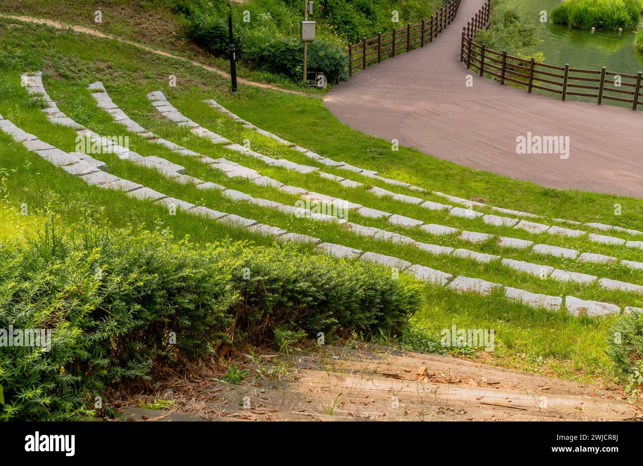 Amphitheater seating in public park made of concrete blocks with pond ...