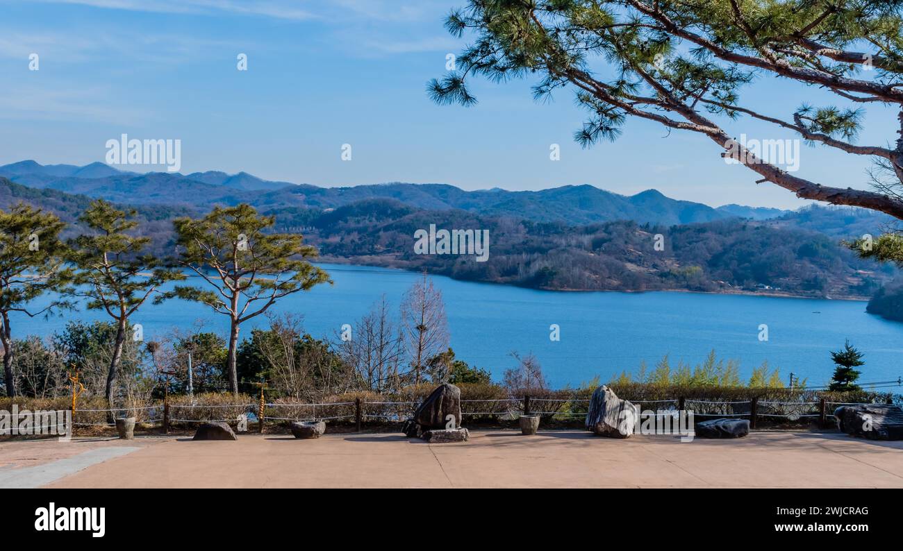 Large boulders placed in row along rope fence at public park with lake ...