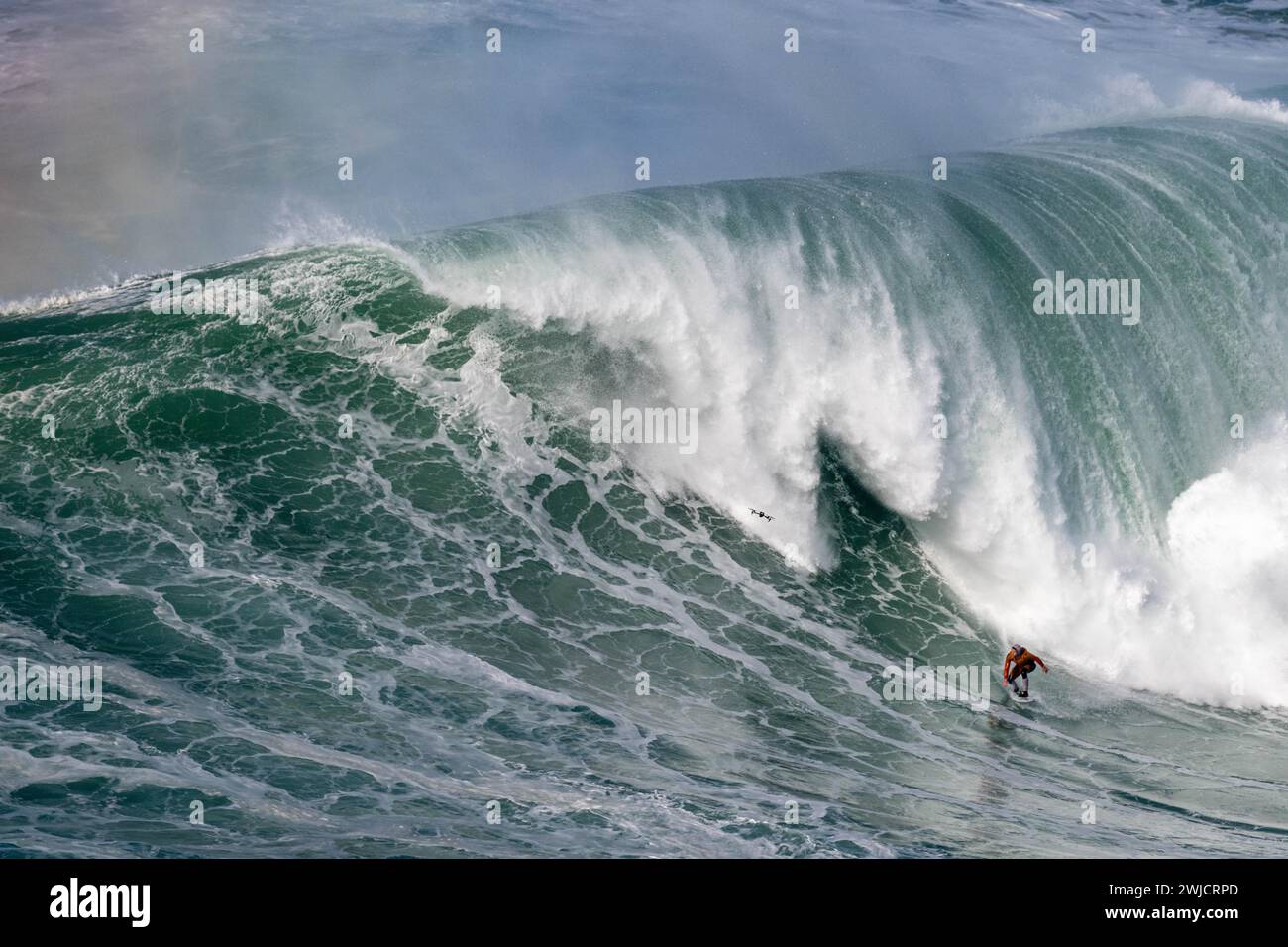 A surfer rides a crashing wave and is filmed with a drone, Nazare ...