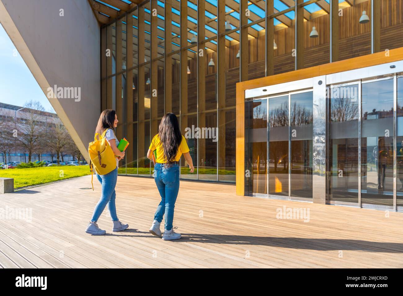 Rear view of two multi-ethnic female students entering to the ...