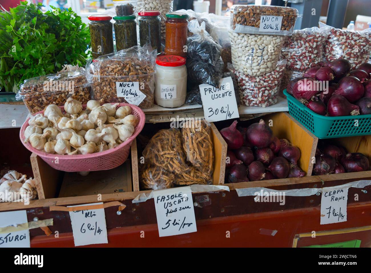 Various dried fruits, onions and nuts in jars on a market stall with ...