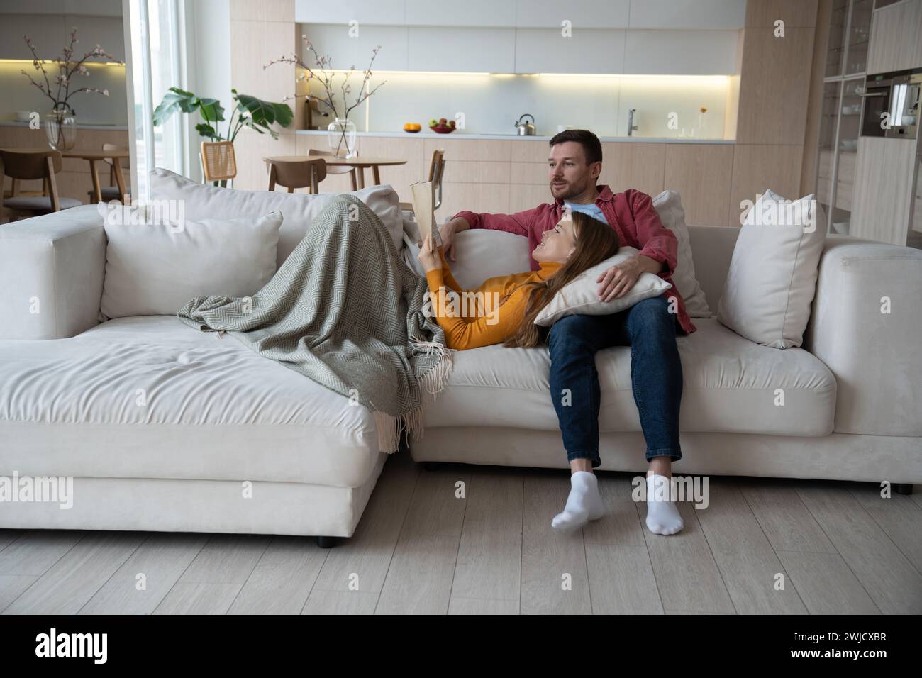 Married couple spending lazy weekend at home, reading and discussing ...