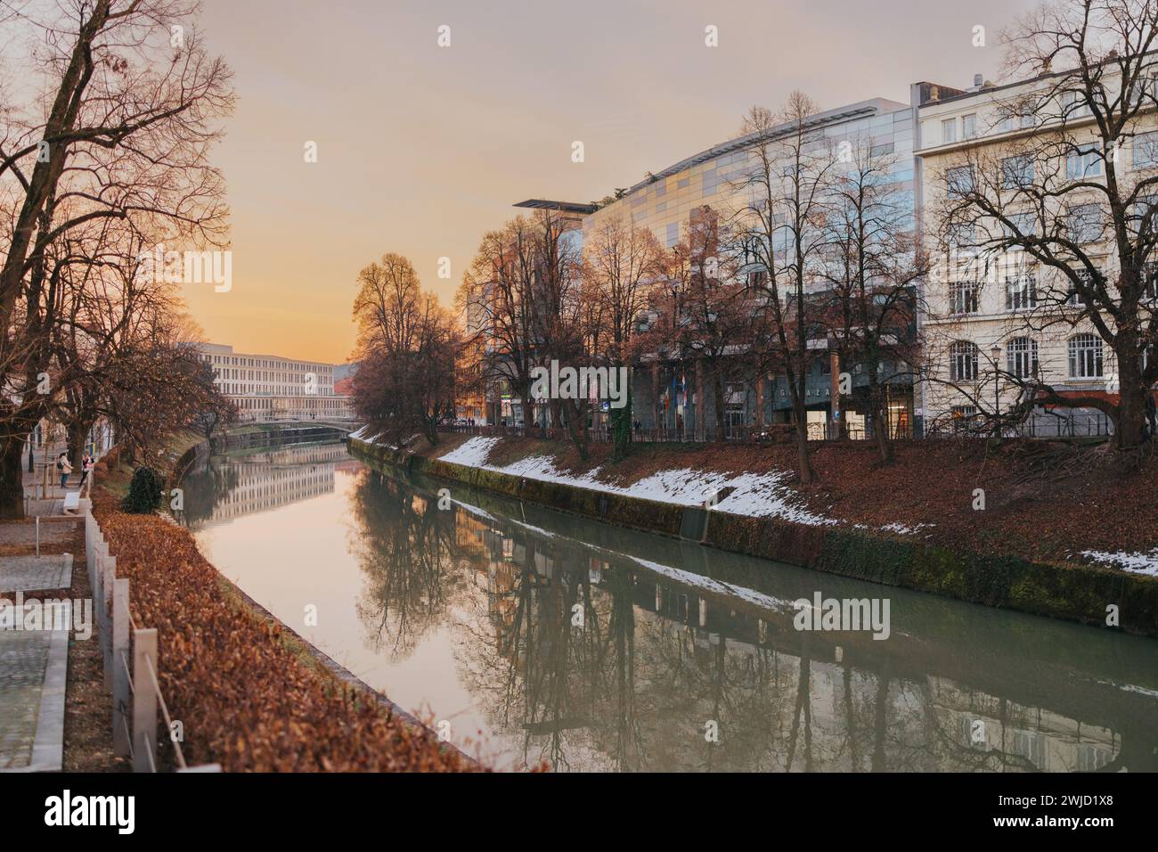 A city street with buildings on both sides and a stream flowing below ...