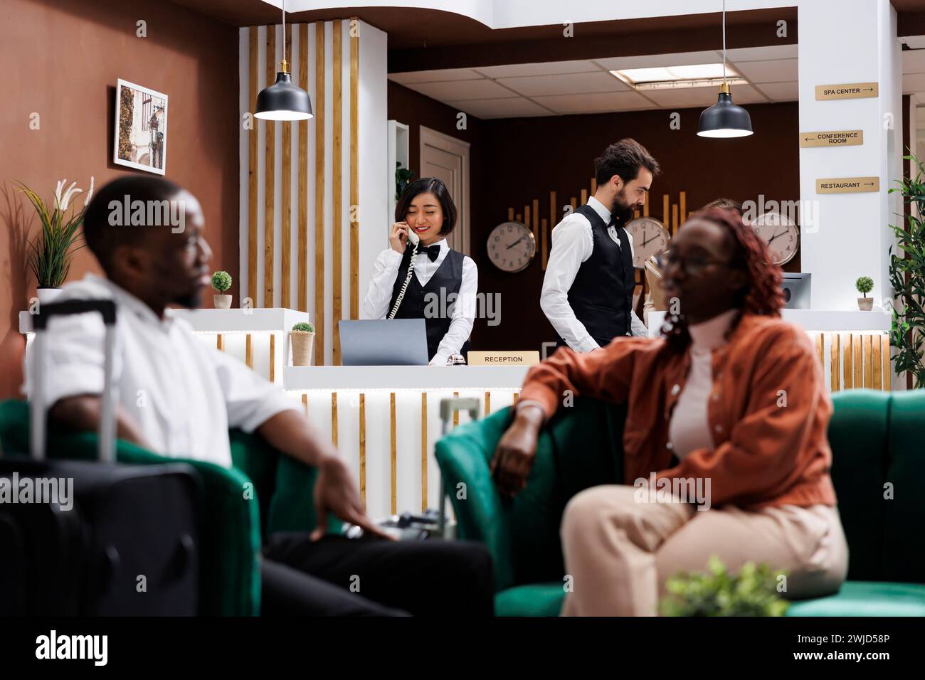 Employees working at front desk in hotel lobby, checking records and ...