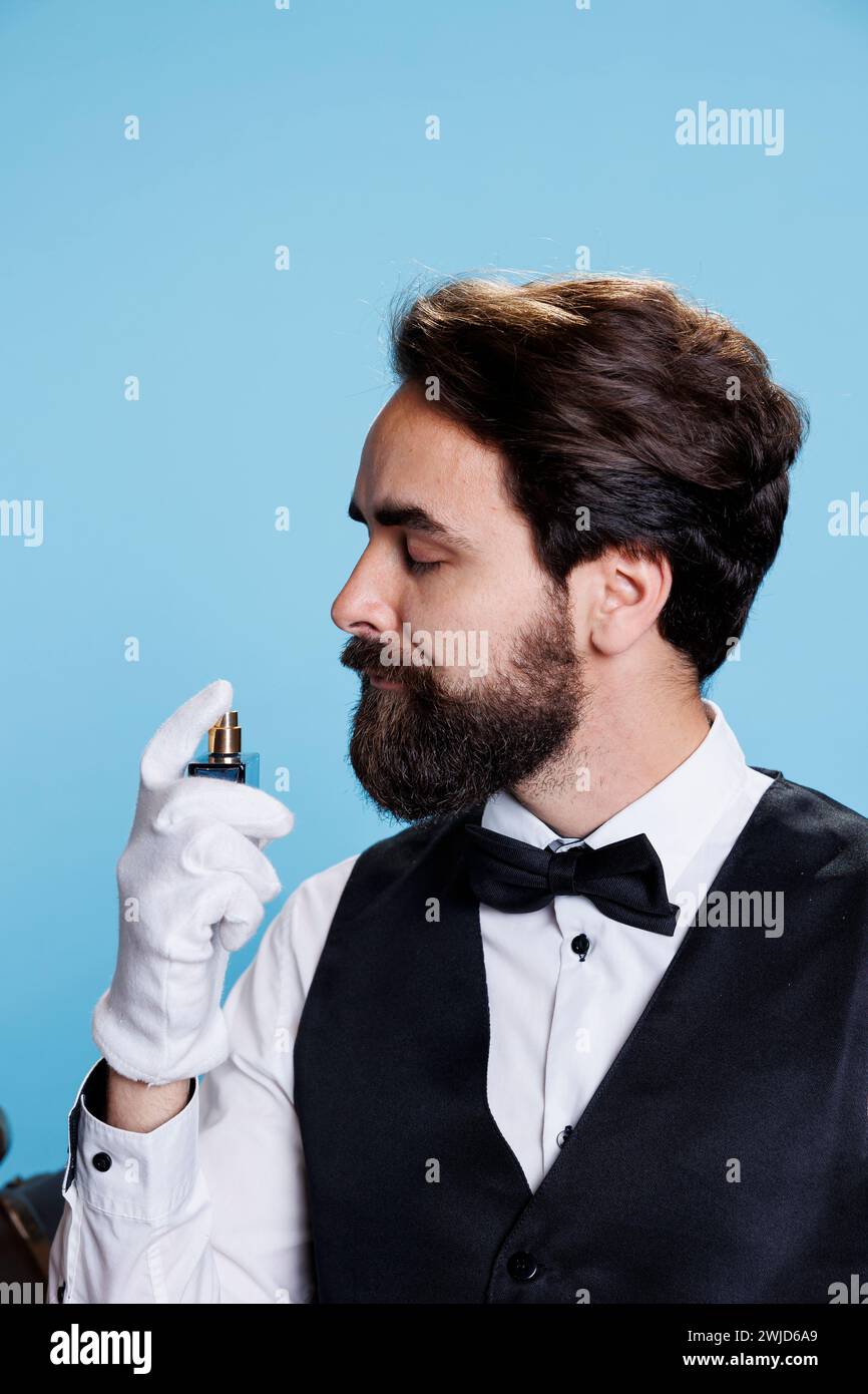 Hotel porter using cologne bottle to smell nice, applying perfume on ...