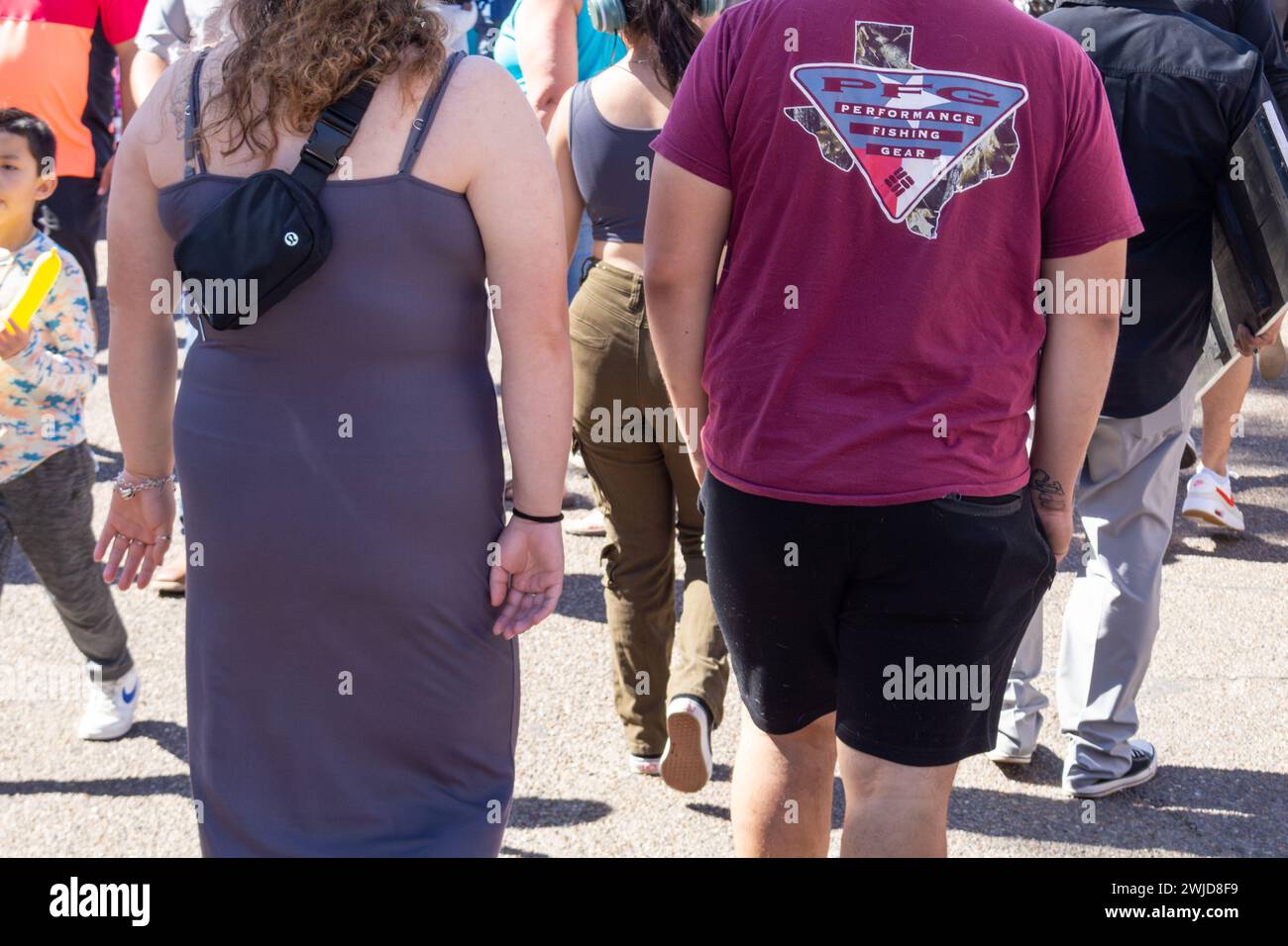 A couple walk in a crow, the woman walking with her arms pronated so ...