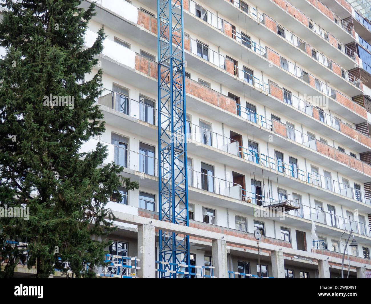 facade of an unfinished high-rise building. Construction crane near a ...