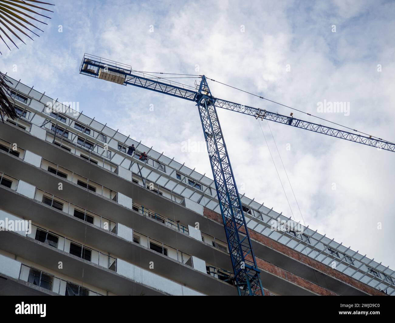 facade of an unfinished high-rise building. Construction crane near a ...
