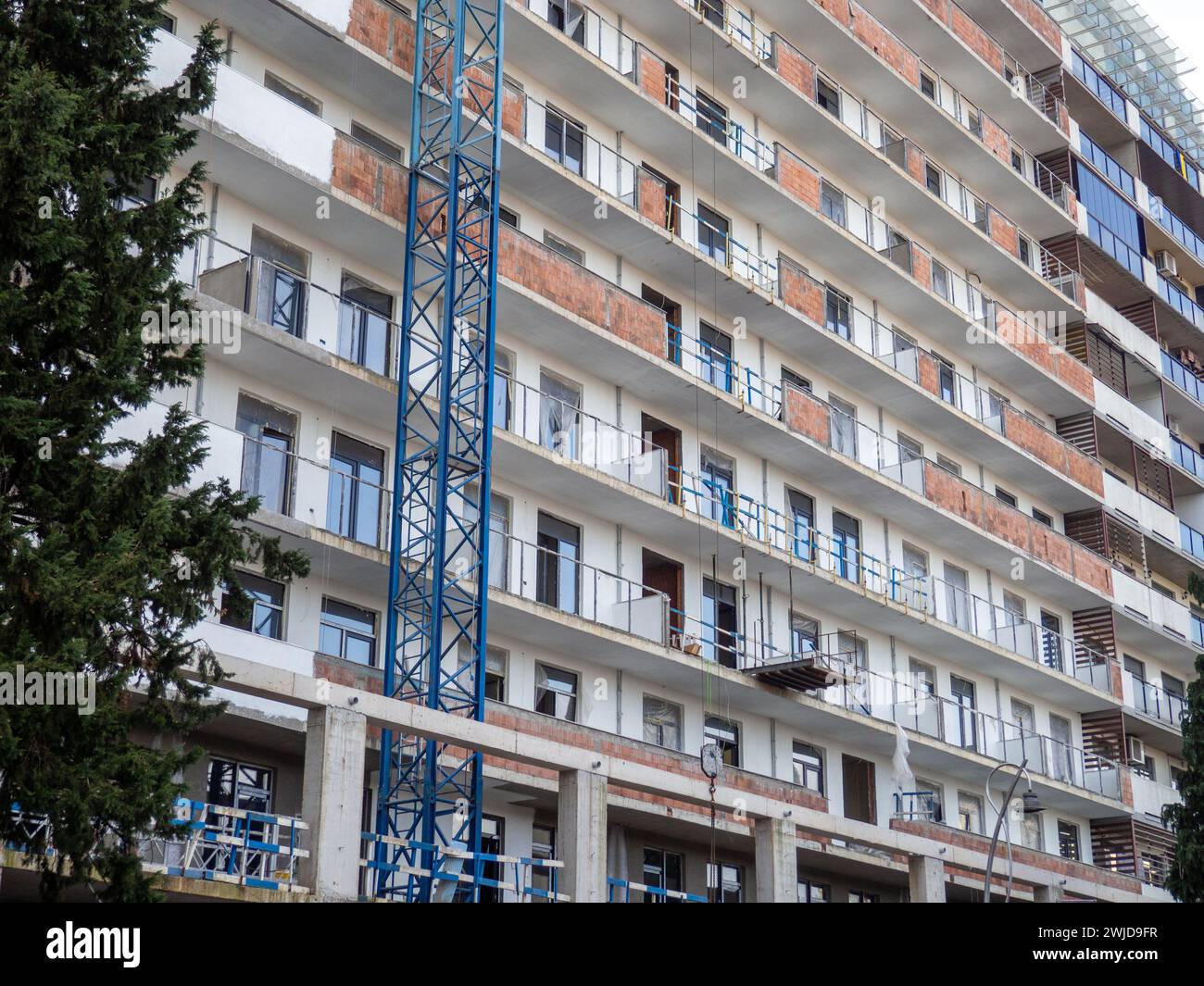 facade of an unfinished high-rise building. Construction crane near a ...