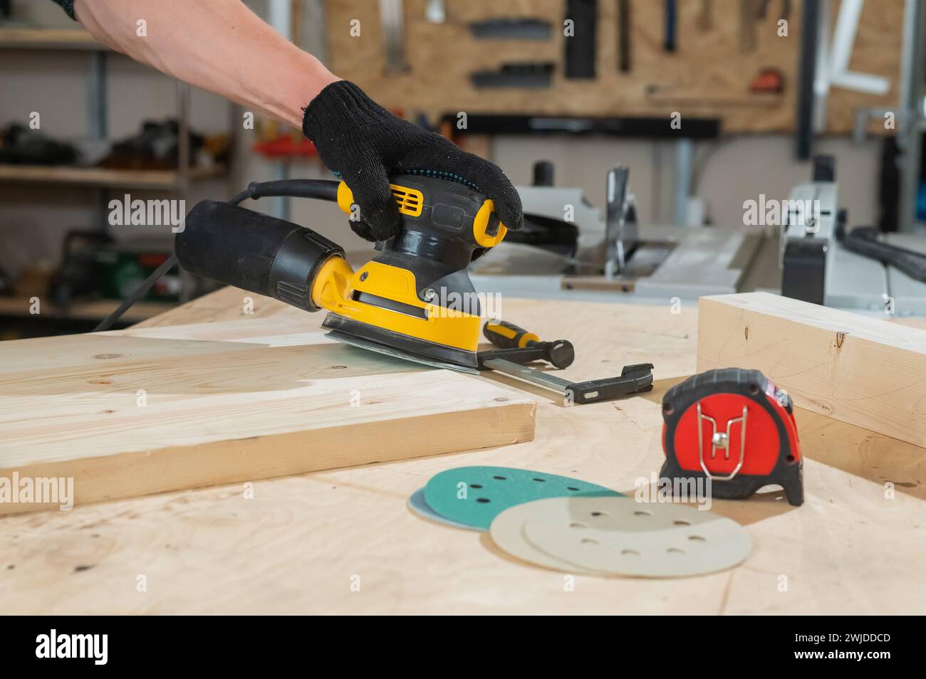 A man using an orbital wood sander in a workshop. Close-up of a ...
