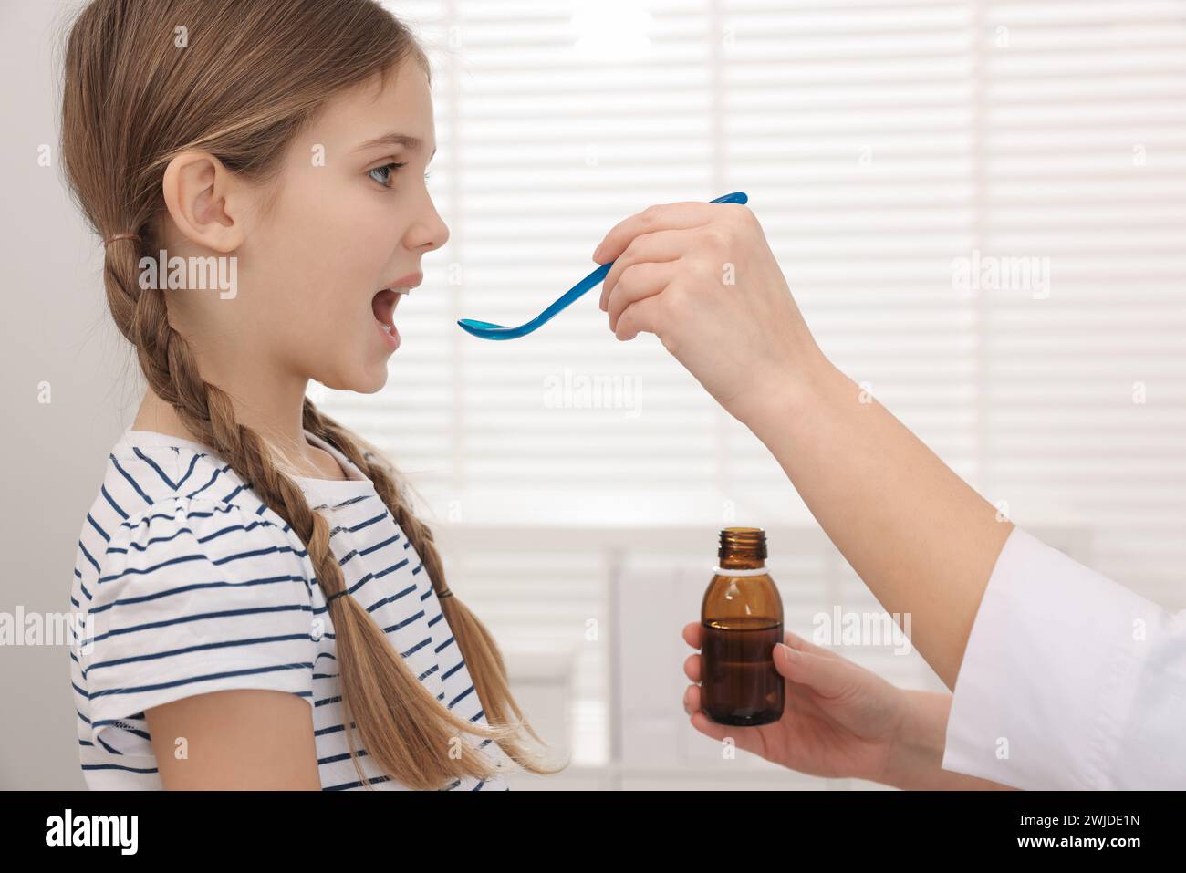 Doctor giving cough syrup to girl in clinic Stock Photo - Alamy