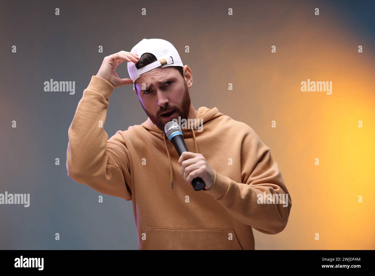 Singer with microphone rapping in color lights Stock Photo - Alamy