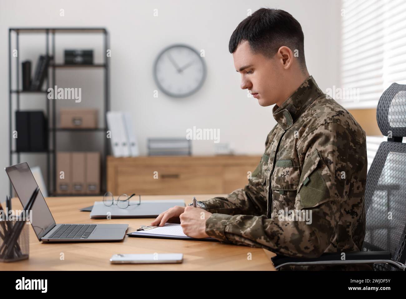 Military service. Young soldier working at wooden table in office Stock ...