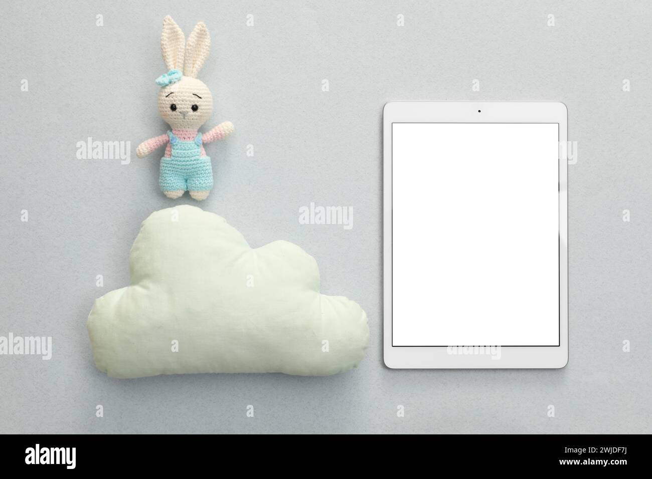 Modern tablet, toy cloud and bunny on light background, flat lay. Space ...