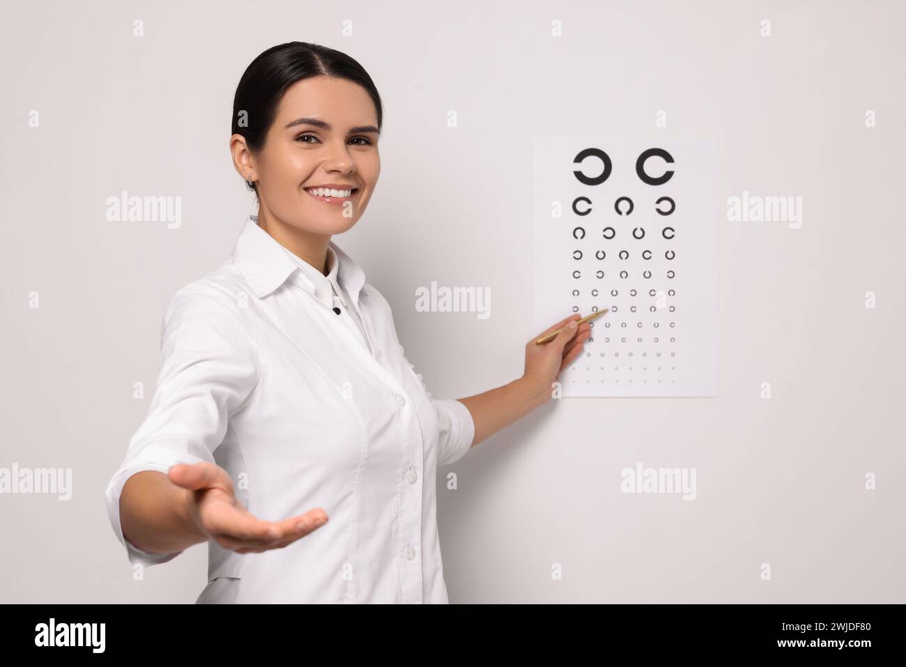 Ophthalmologist pointing at vision test chart on white wall Stock Photo ...
