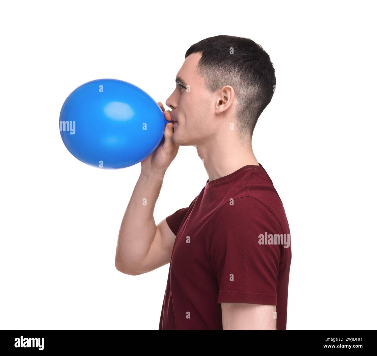 Young man inflating light blue balloon on white background Stock Photo ...