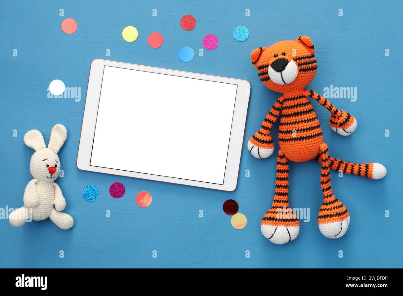Modern tablet, confetti and stuffed animals on blue background, flat ...
