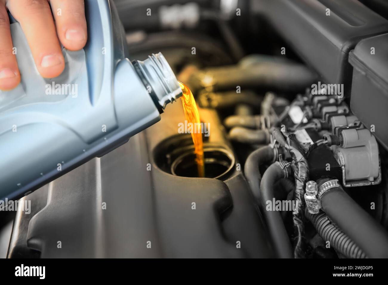 Man pouring motor oil into car engine, closeup. Color accent effect ...