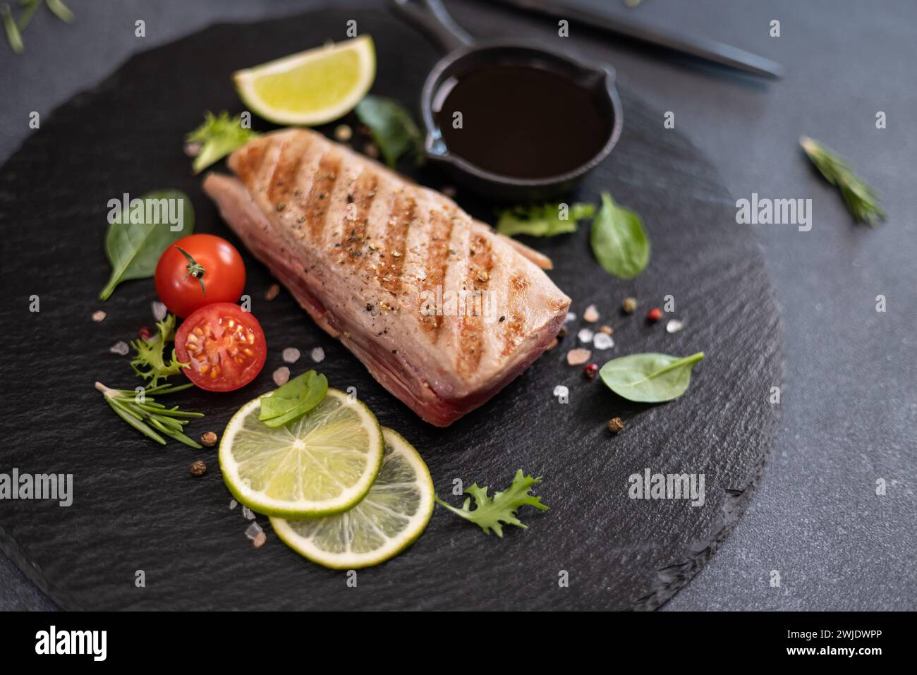 grilled cooked piece of tuna fillet on black stone serving board Stock ...