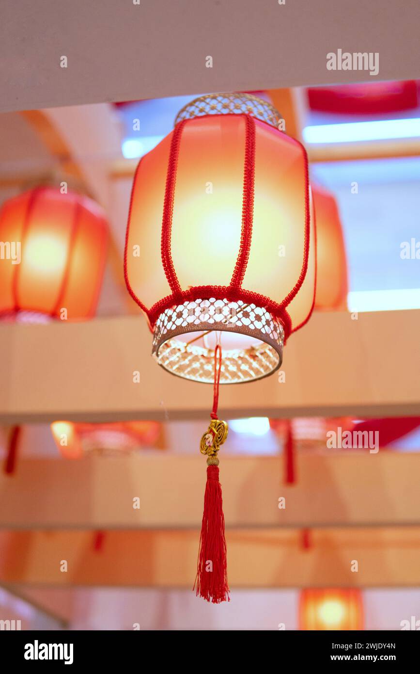 A row of orange paper lanterns hanging from a ceiling. The lanterns are ...