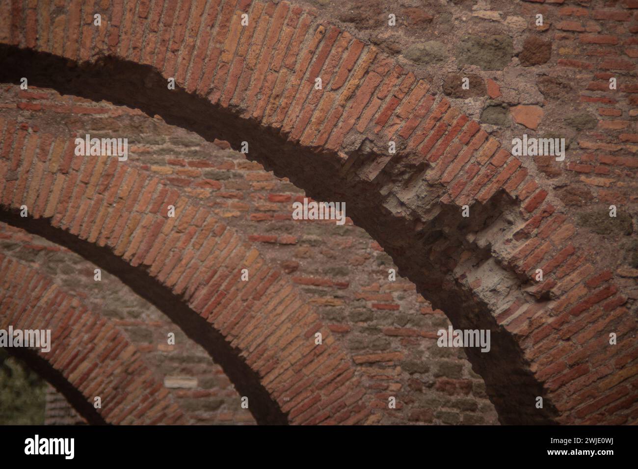 Brick wall or arch falling apart. View of an old brick alley with ...