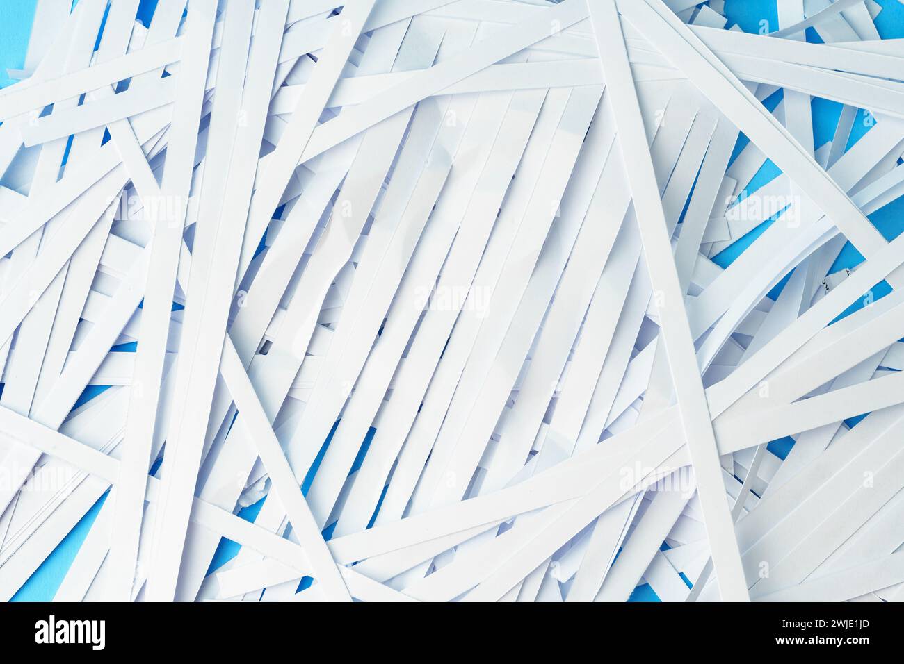 Shredded paper pieces on a blue background Stock Photo - Alamy