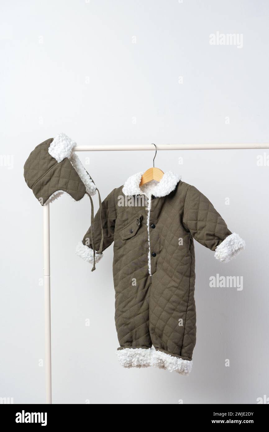 Baby gray quilted winter overalls on hanger against white wall Stock ...