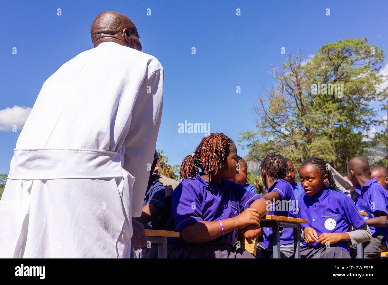 A dedicated teacher and uniformed students engaged in an open-air ...