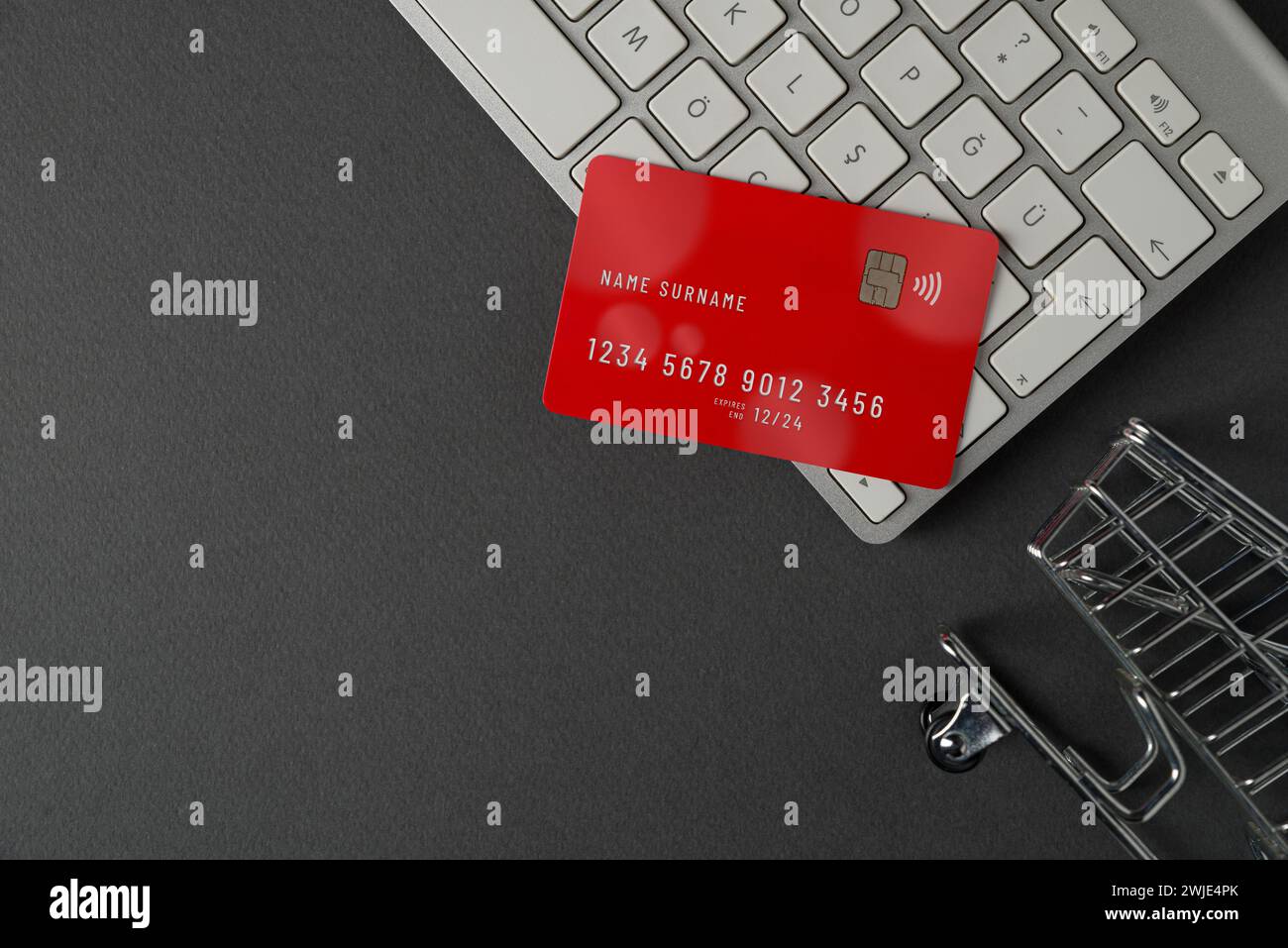 Top view of computer keyboard, credit card and mini market cart on dark ...