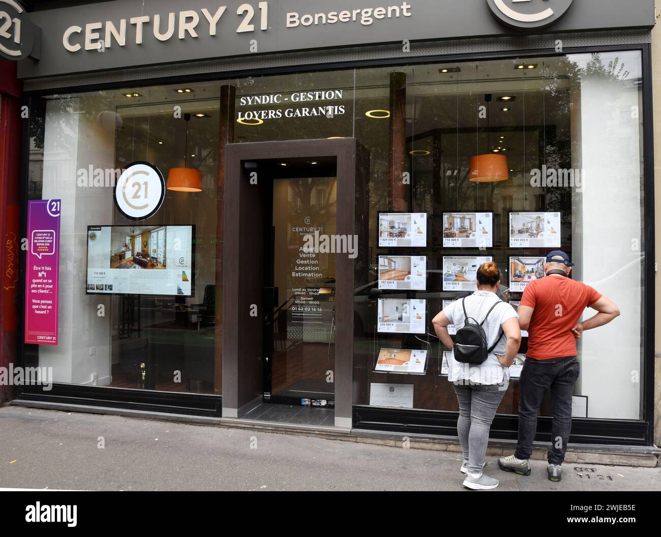Estate agency Century 21 in Paris (France). Couple looking at the ...
