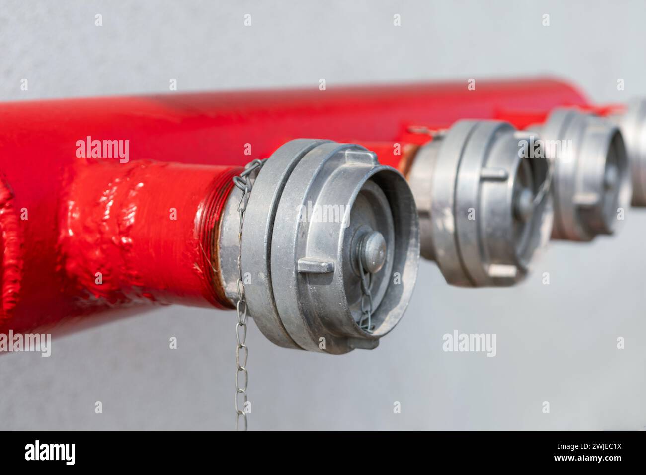 Red fire hose and water tap on white wall background Stock Photo - Alamy