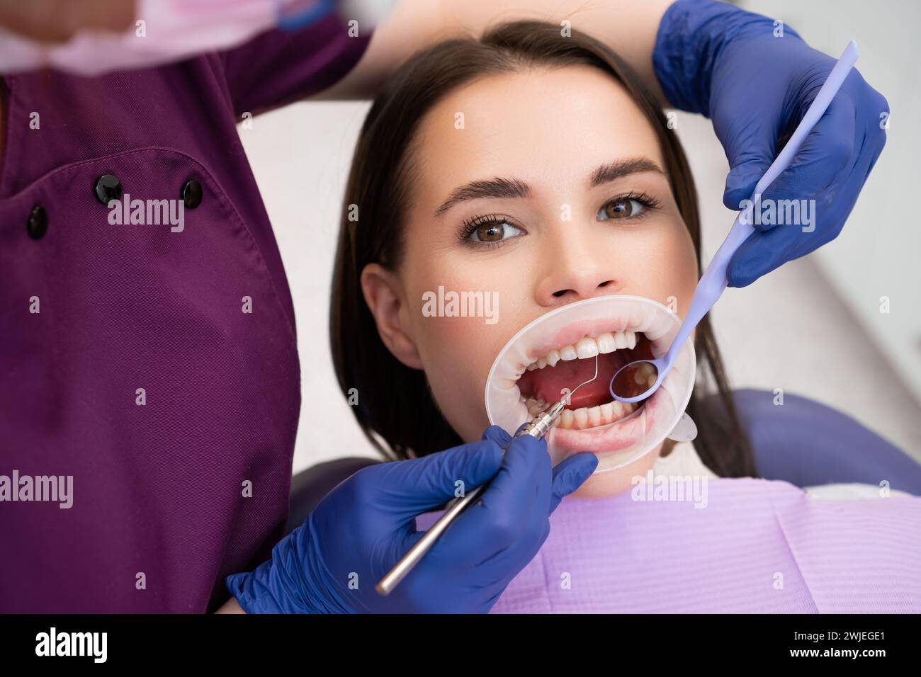 Female dentist blows air across teeth drying surface from saliva for ...