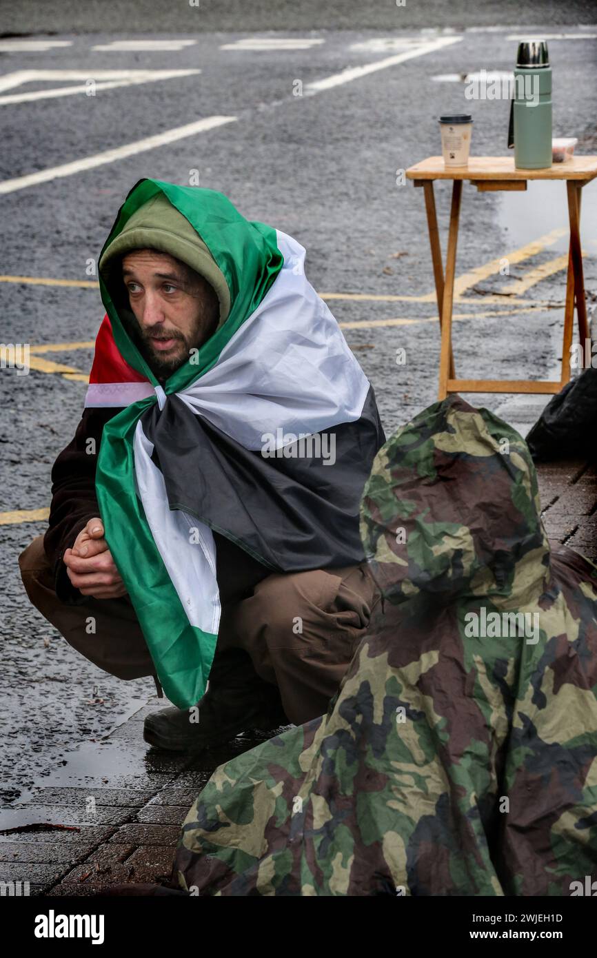 A supporter wearing a Palestinian flag as a cape talks to one protester ...