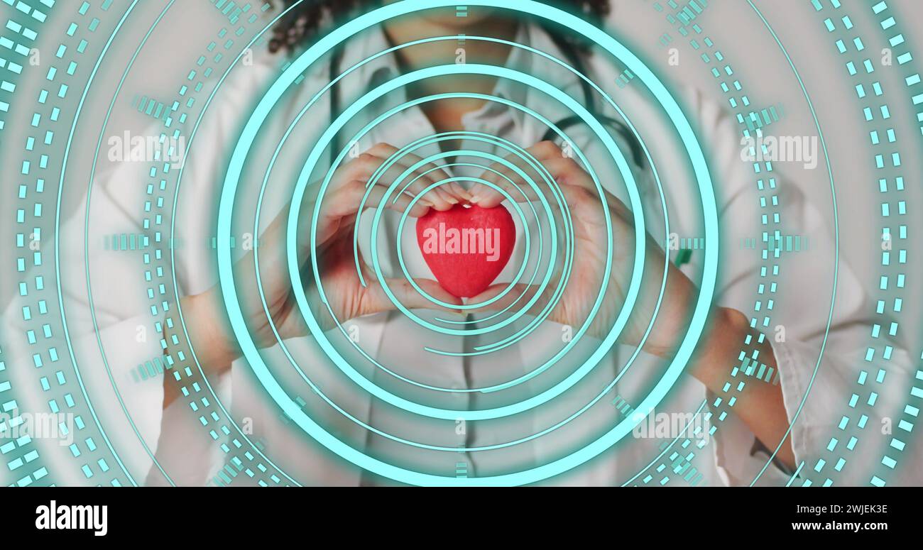 Image of scope scanning over biracial female doctor holding heart Stock ...