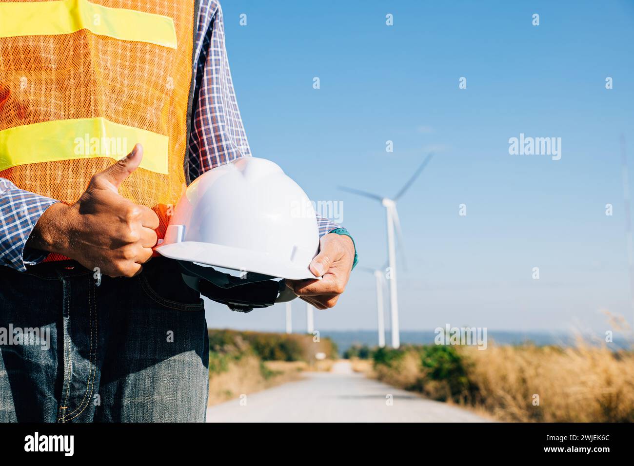 Engineer holding safety helmet stands at windmill field Stock Photo - Alamy
