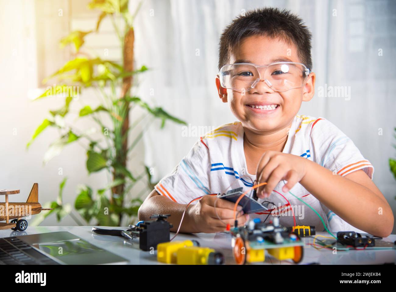 Asian kid boy plugging energy and signal cable to sensor chip with ...