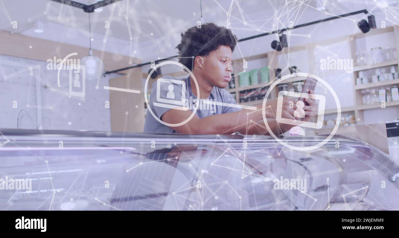 Image of media icons over biracial male shop assistant using smartphone ...