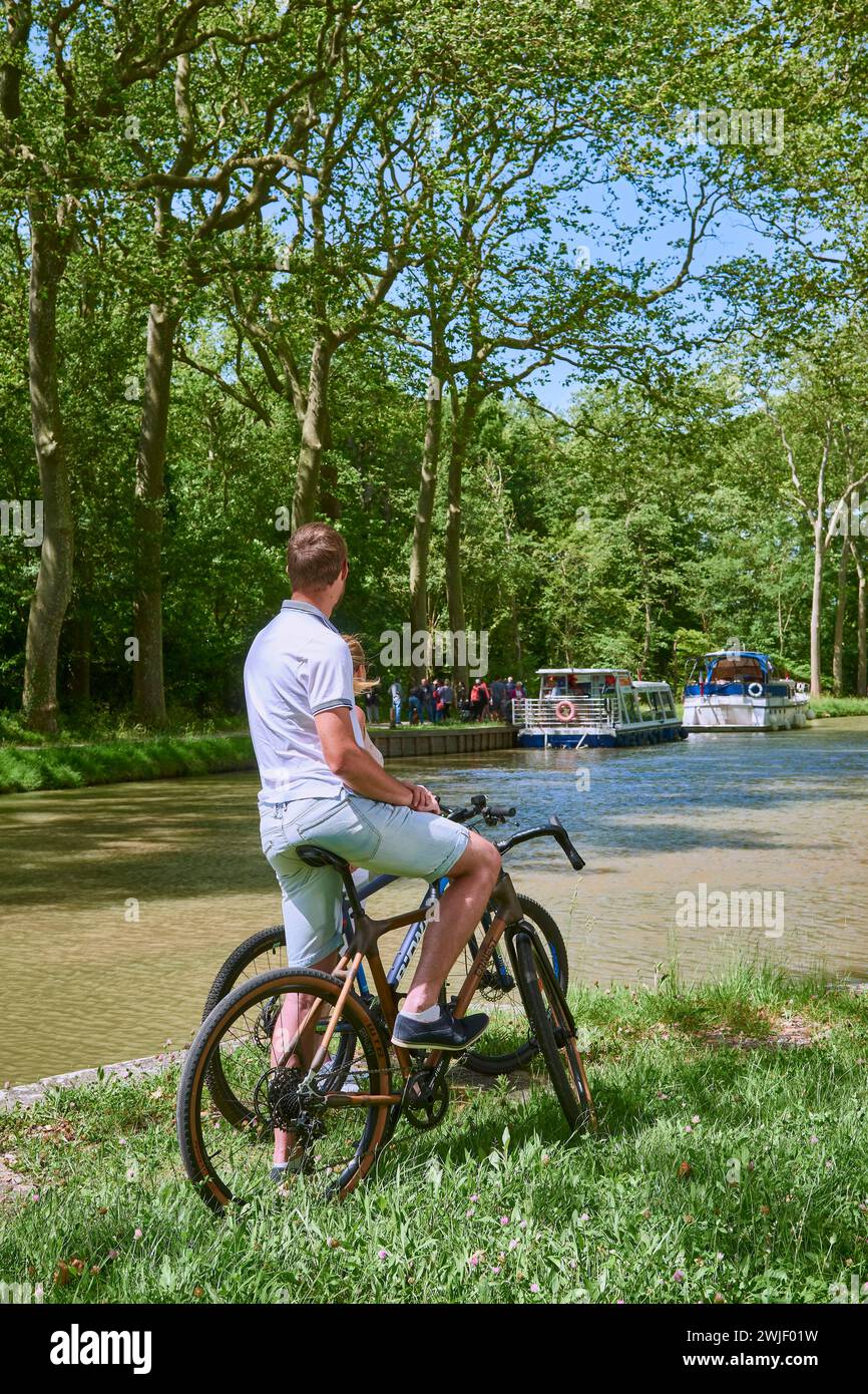 Couple on on bike ride along the canal, barge and lock keeper's house ...