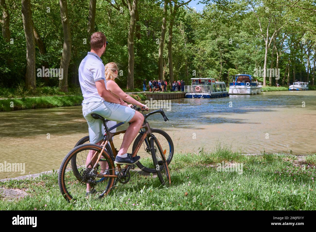 Couple on on bike ride along the canal, barge and lock keeper's house ...