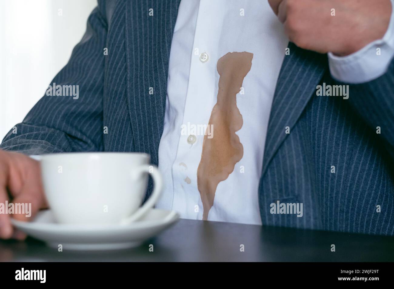Unrecognizable a man in a suit spilled coffee on a white shirt in cafe ...