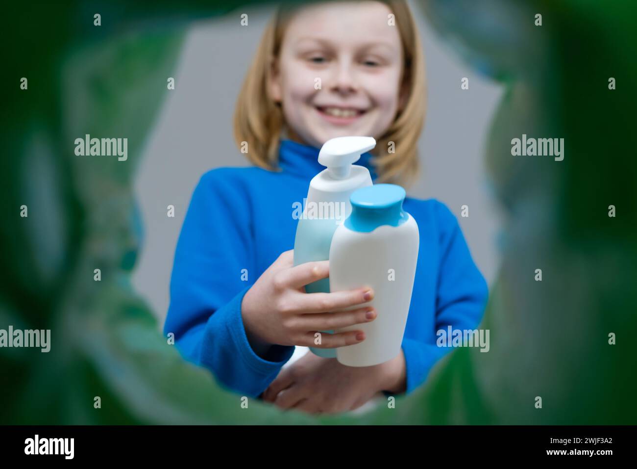 Low angle view a child sorting plastic bottles in recycle bin in home ...