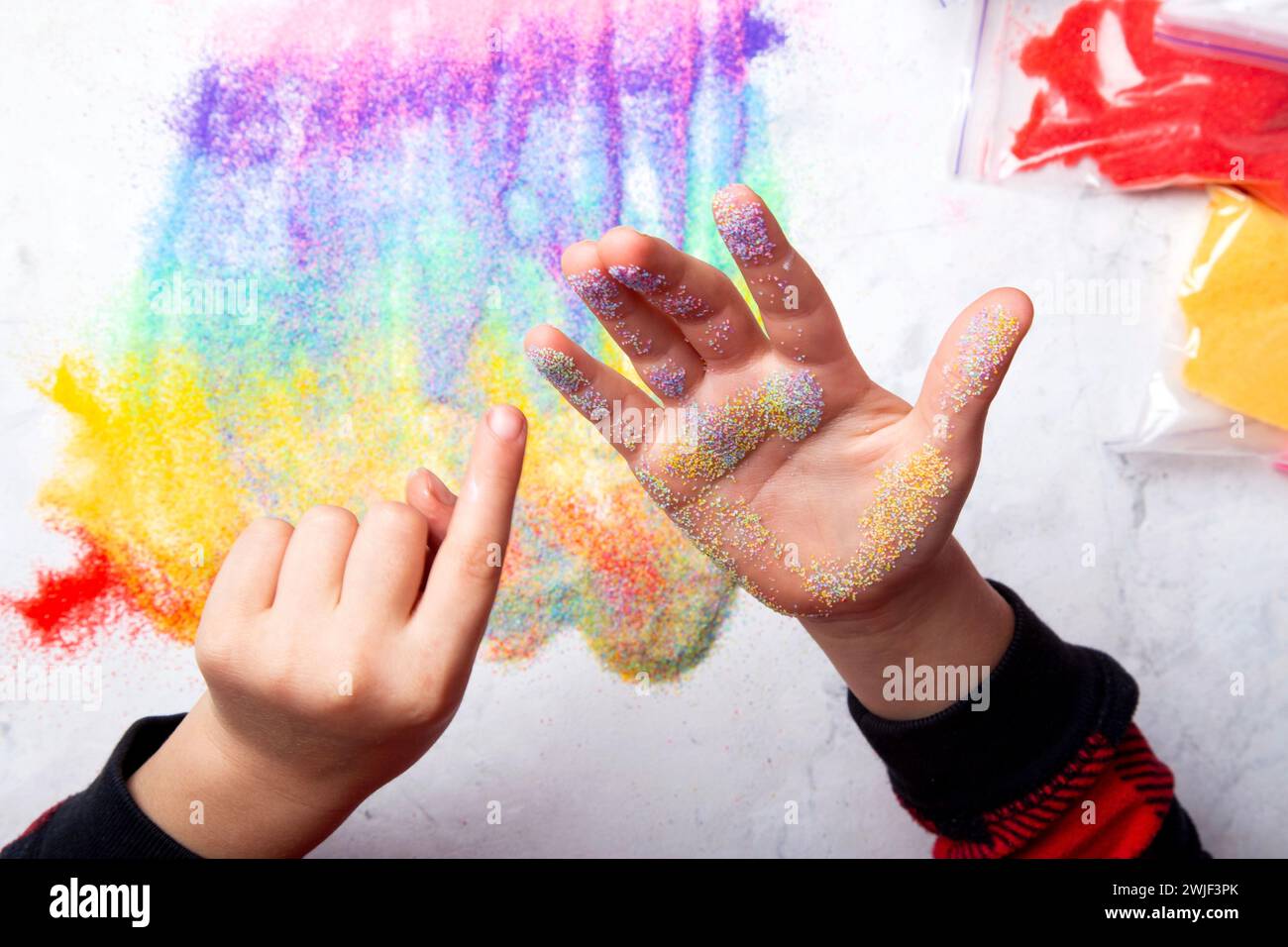 Child hand painting with rainbow colored sand. Touch of colors creating ...