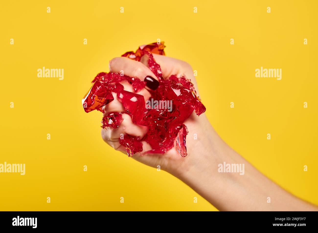 unknown young woman with nail polish squeezing red fresh jello in her ...