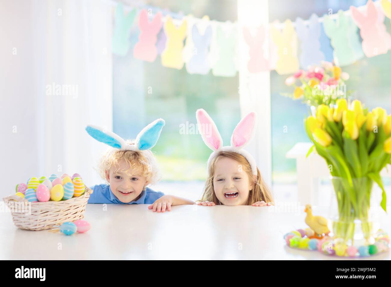 Kids dyeing Easter eggs. Children in bunny ears dye colorful egg for ...