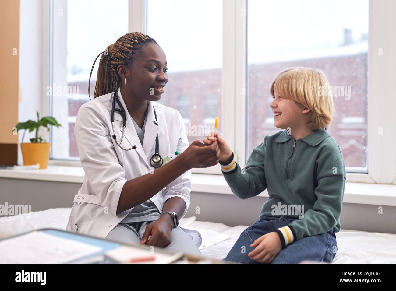 Side view portrait of smiling woman doctor fist bump with little boy in ...