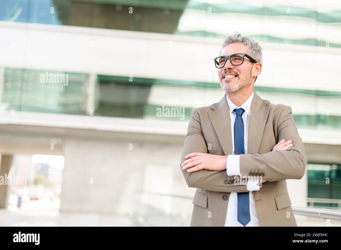 Senior businessman stands confidently with arms crossed in front of a ...