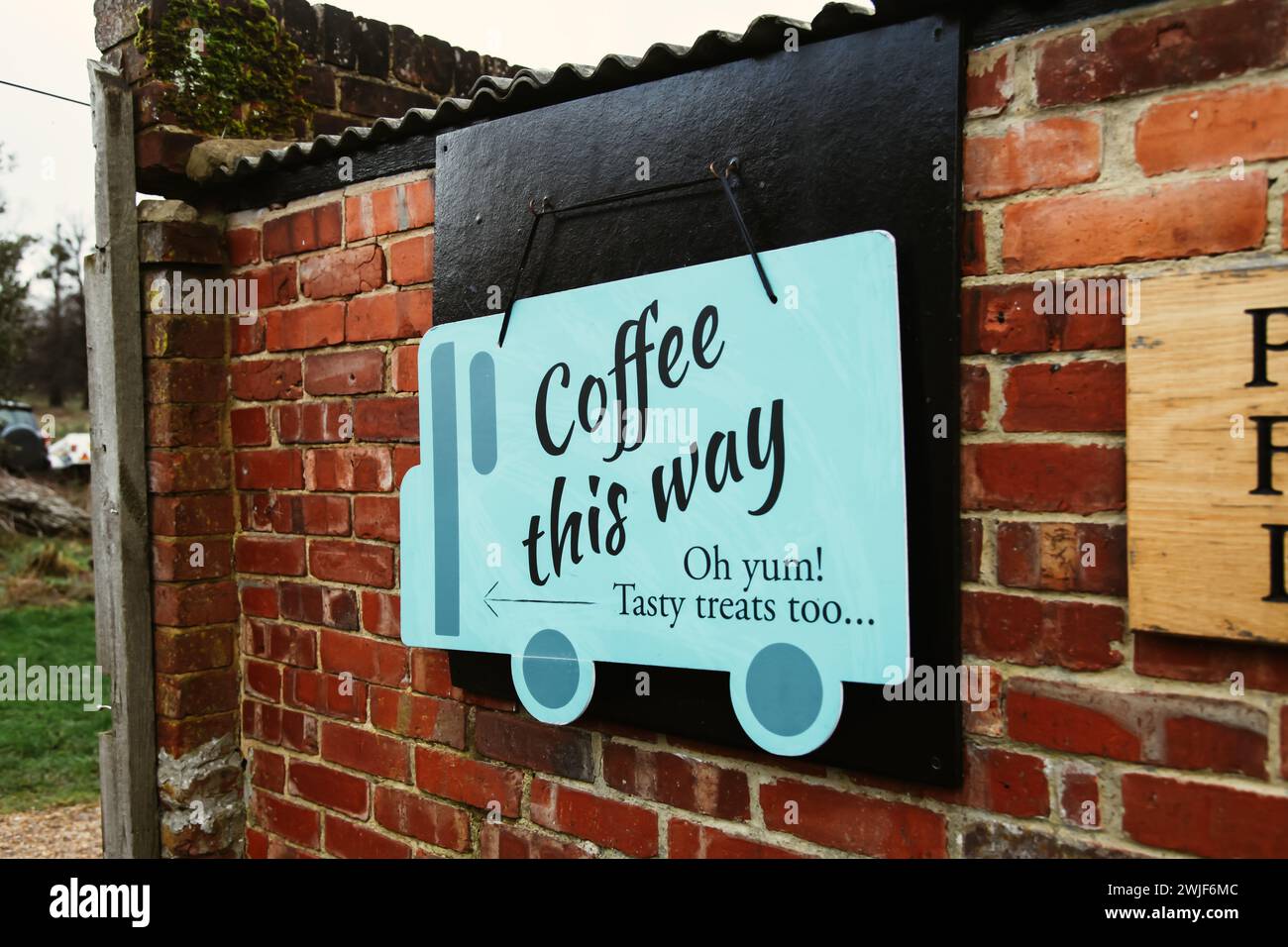 Sign for Coffee this way, hanging on red brick wall, advertising café ...