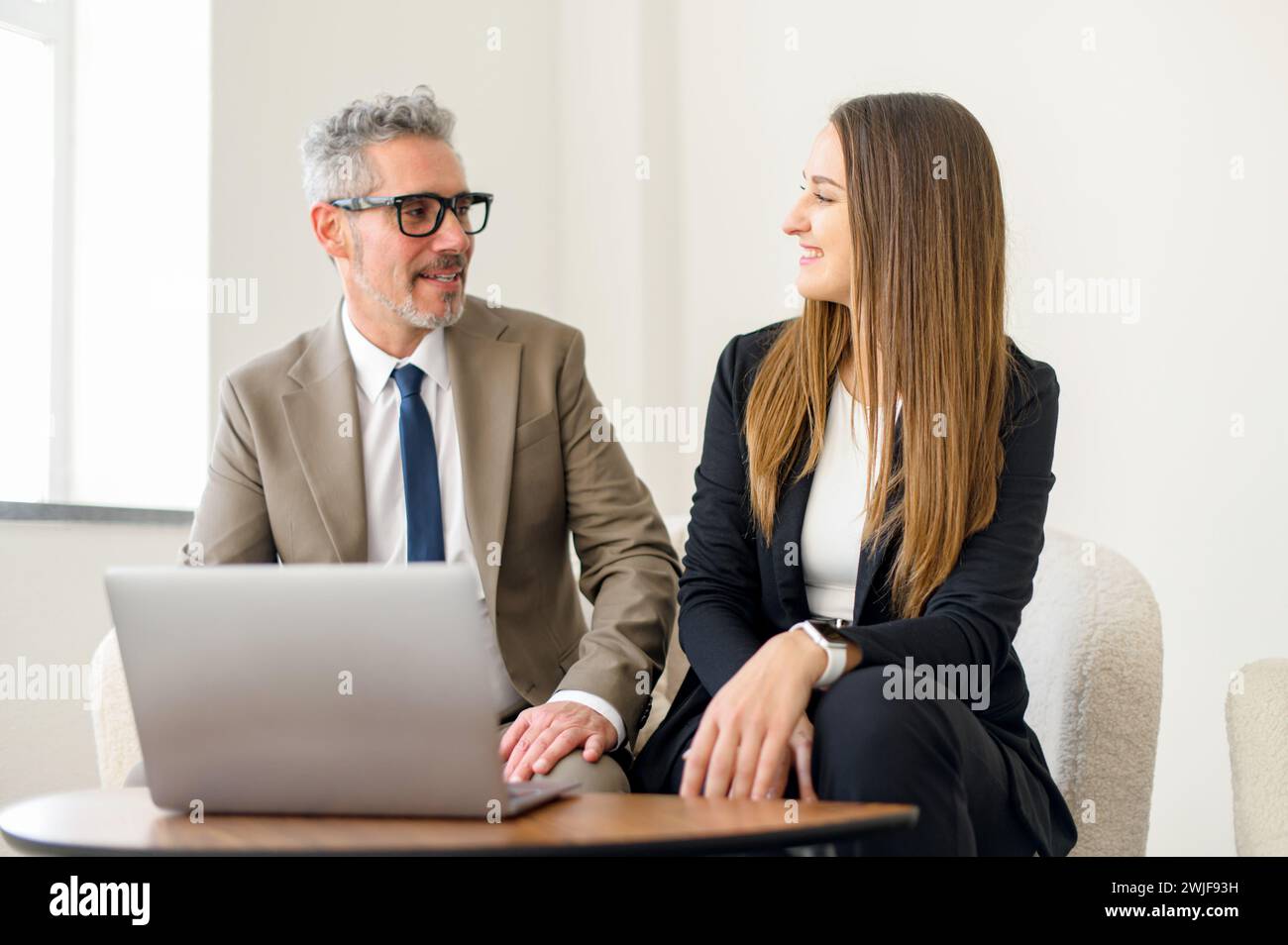 A senior businessman with grey hair and a young female professional ...