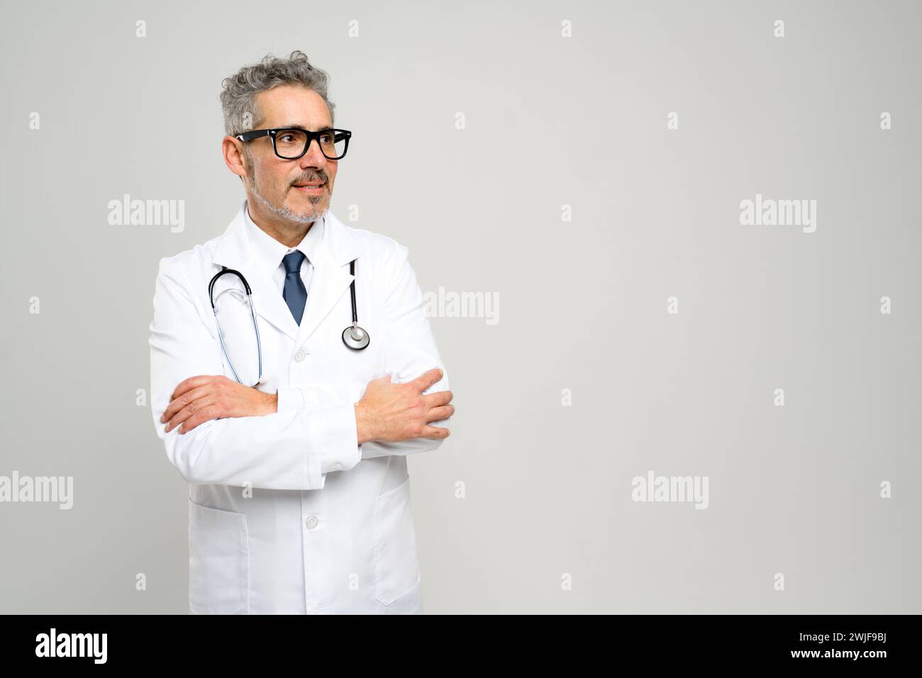 A senior doctor stands with a pleasant demeanor, conveying both ...