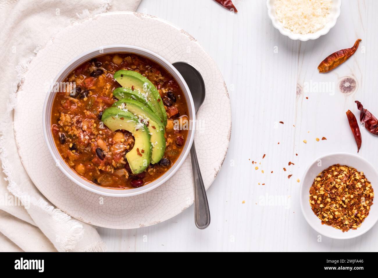 Top down view of a bowl of chili topped with avocado slices and chili ...